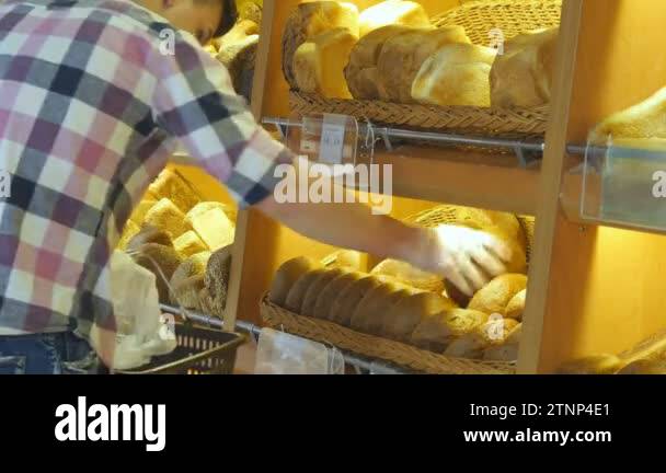 Man chooses and putting a fresh bread loaf into a package in the ...