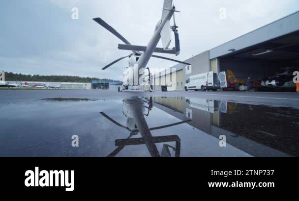 Forwards movement above shallow puddle on area in front of hangar. Low ...