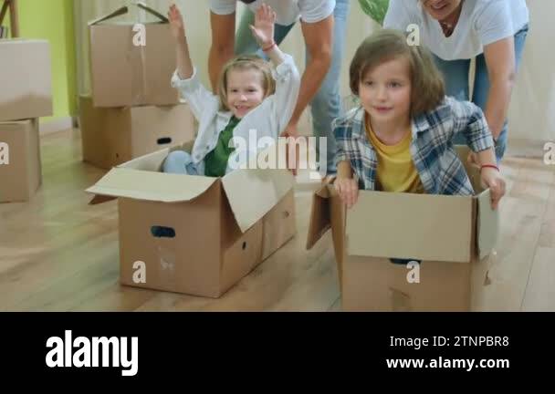 In the large modern living room happy kids have a ride on the boxes ...