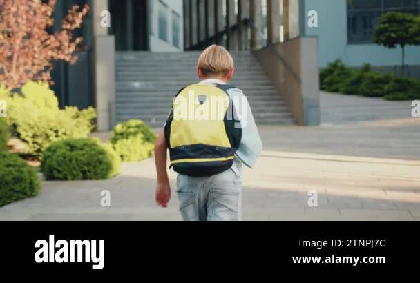 School boy child with backpack alone going running to modern school ...