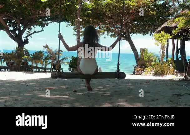 Serene Back View of Woman in white Swimsuit Swinging on Beach ...