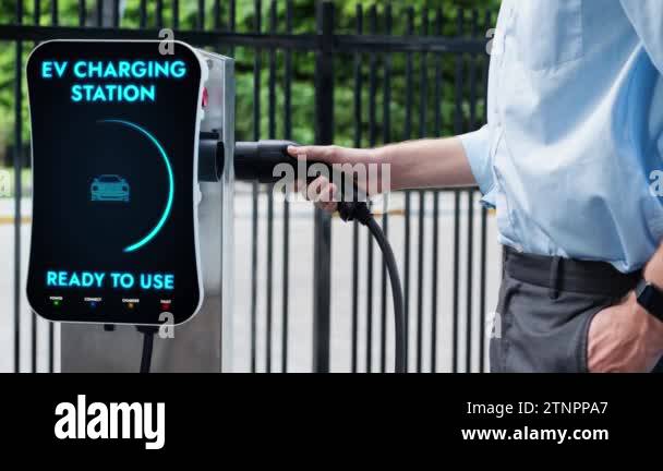 Businessman pull out EV charger from charging station to recharge ...