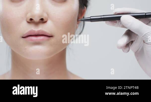Asian woman with dark hair and hand in white glove holding marker on ...