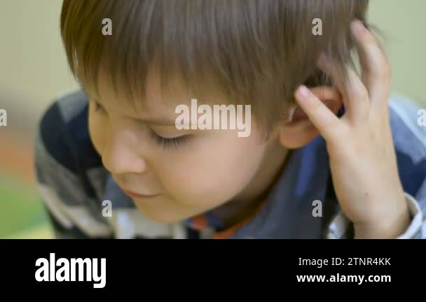 Camera focuses on cute little boy. He looking in camera and touching ...