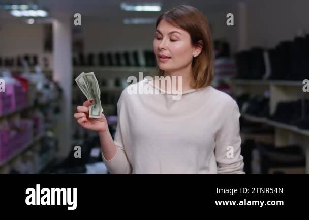 Portrait of smiling confident beautiful woman standing with cash in ...