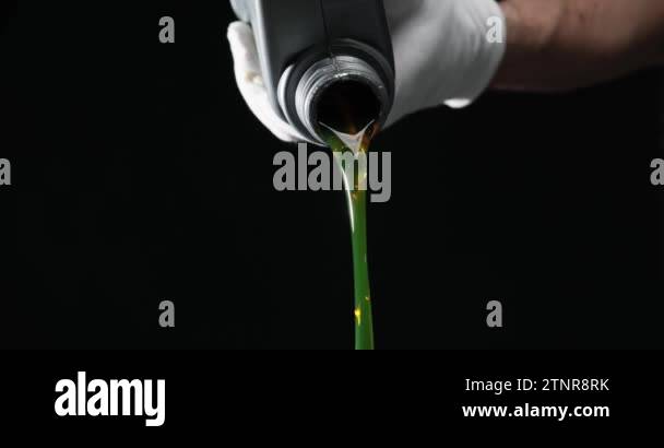 Mechanic wearing white gloves pours car engine oil from plastic bottle ...