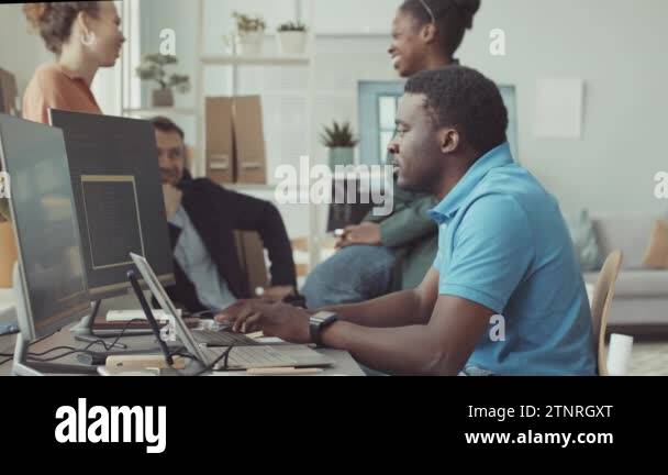 Waist up slowmo of young Black man coding on pc while his young ...