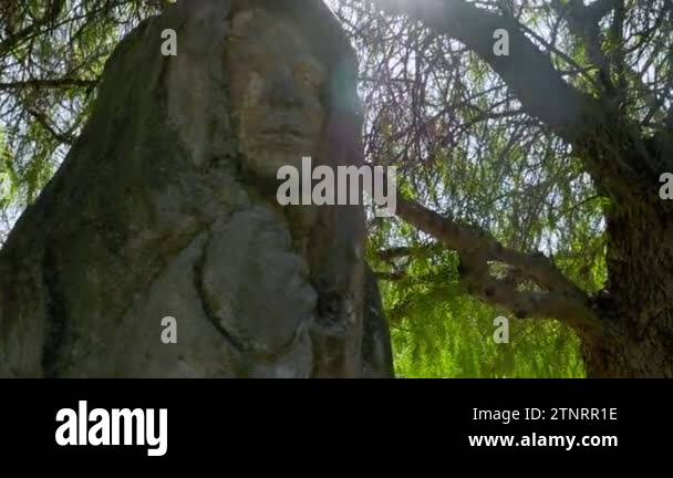 Ancient stone statue of the Madonna Virgin Mary in a forest in the ...