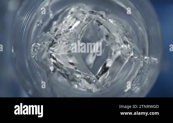 Super Slow Motion Detail Shot of Ice Cube Falling into Glass with Vodka ...