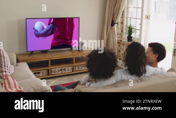 Biracial family watching tv with african american male rugby player ...