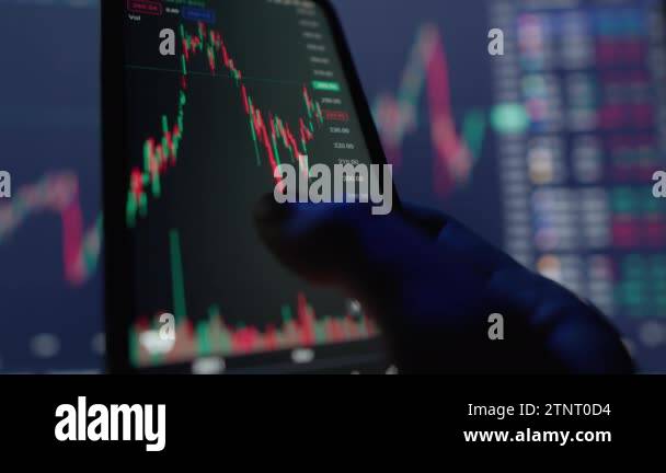 The investor analyzes trading data and charts on his smartphone to make ...