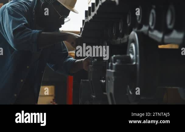 Black male service technician in denim shirt and hard hat using wrench ...