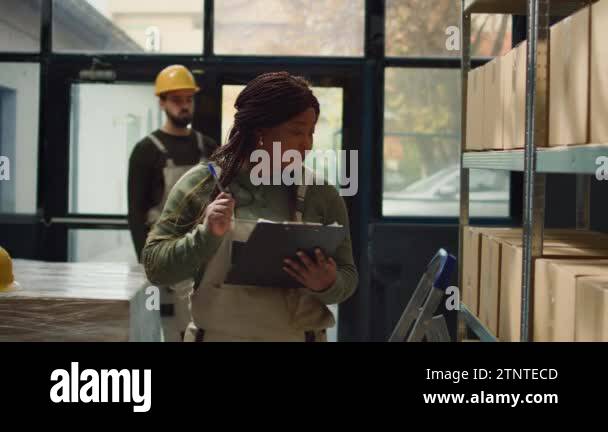 Dolly out tracking shot of african american woman in warehouse inputing ...