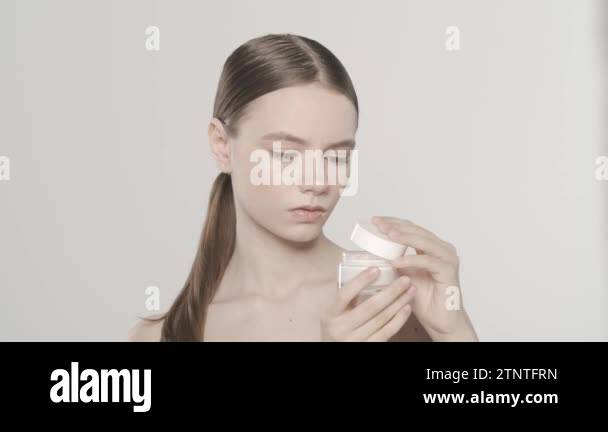 Portrait of a young brunette female model holding a cosmetics product ...