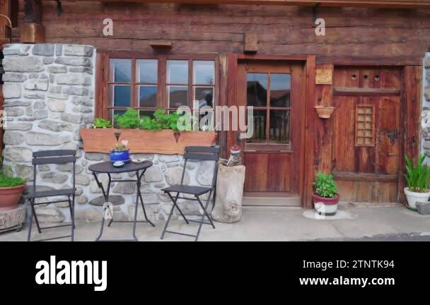 Traditional Swiss rustic wooden facade. Door, windows, and chairs ...