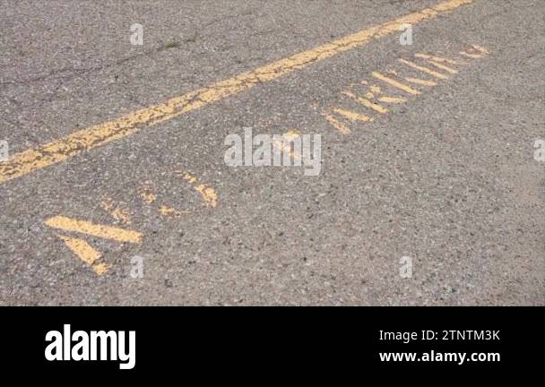 no parking caption print text writing in yellow below line on pavement ...