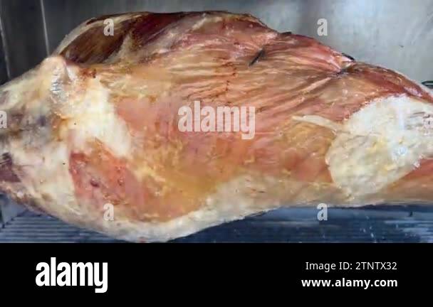 Roasting whole lamb on a spit metal rotating stick over fire, golden ...