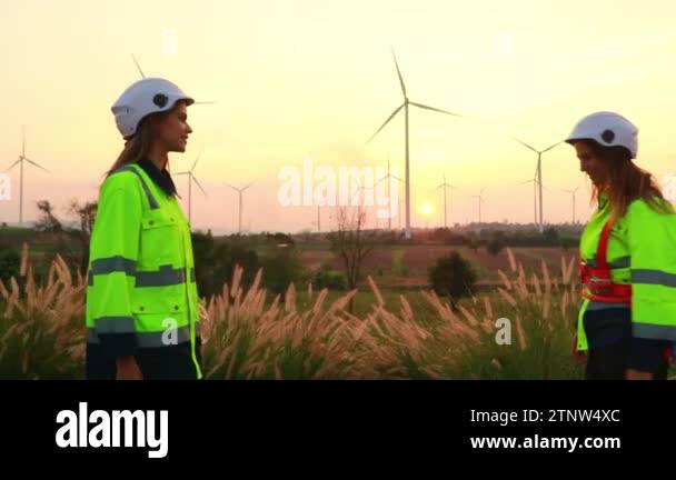 Portrait two female technicians, good colleague shaking hands together at windmill field in ...