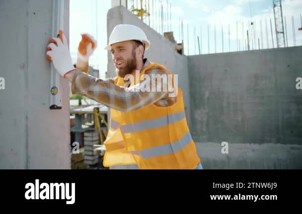 A young worker checks the level of the wall with a spirit level ...