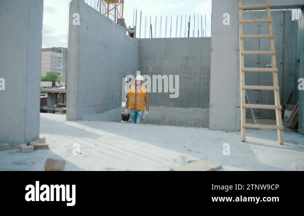 young male civil engineer wearing a safety helmet climbs the stairs ...