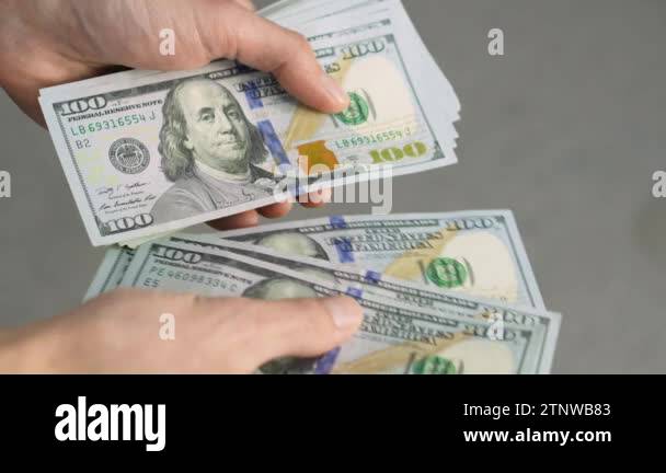 Mens hands carefully count hundred-dollar bills, performing an accurate ...