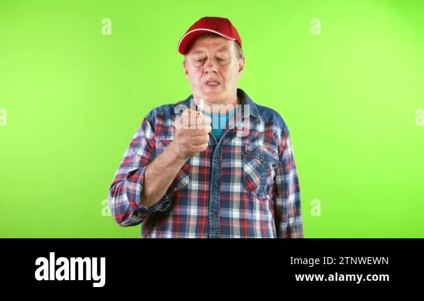 Old man in red baseball cap lighting and and blows out bright fire gas ...