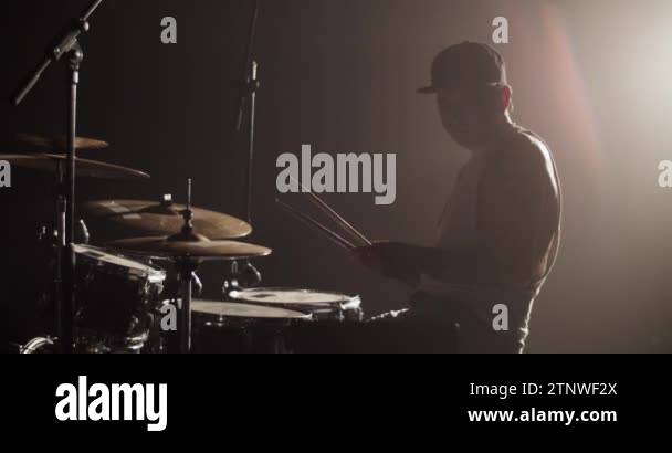Side view of male drummer putting on headphone in ear and playing rock ...