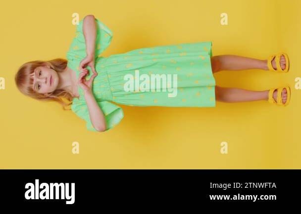 I love you. Smiling blonde school girl makes heart gesture demonstrates ...