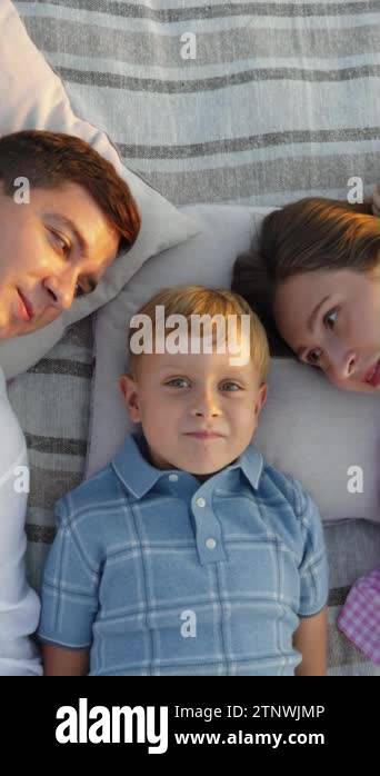 Vertical Screen: Parents and little son lying on blanket in open air ...