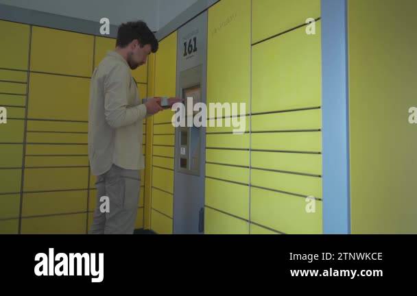 Man uses yellow packing station to send package by self-service. German ...