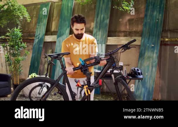 Young dedicated man gripping and moving broken bicycle to repair-stand ...
