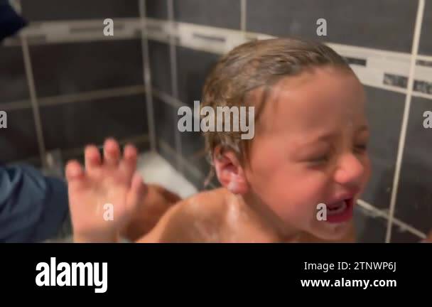 Crying child taking bath. A tearful little boy cries while bathing in ...