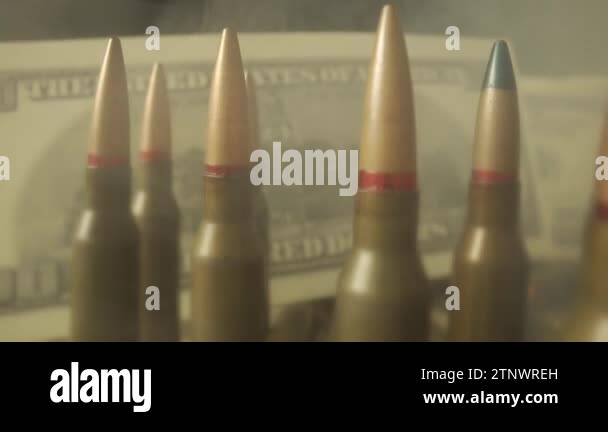 Rows of rifle cartridges on the background of dollar bills close up. Rifle ammunition is ...