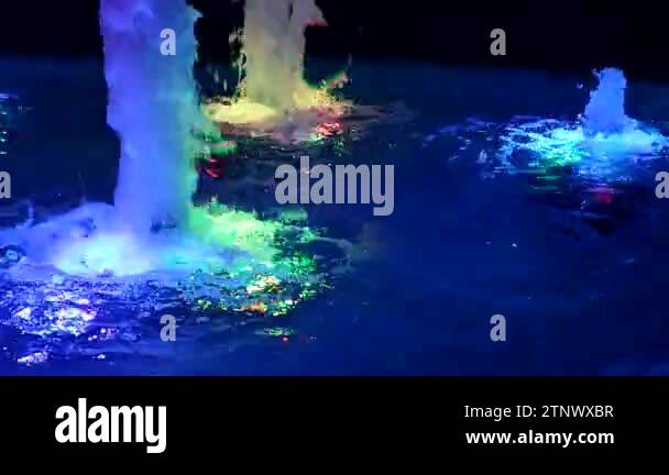 Fountain in water illuminated by colorful lights at night. Flow of ...