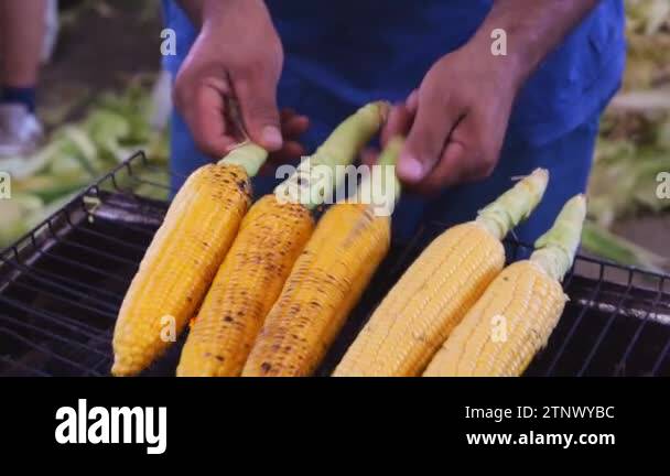 Mans hands turn over grilled corn on the cob, cooking corn at home ...