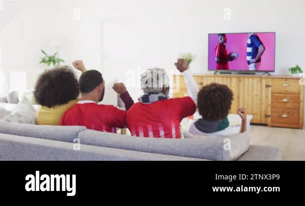 Biracial family watching tv with diverse male rugby players with ball ...