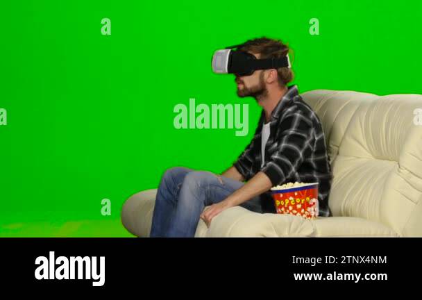 Man in VR mask watching a movie and eating popcorn. Green screen Stock ...