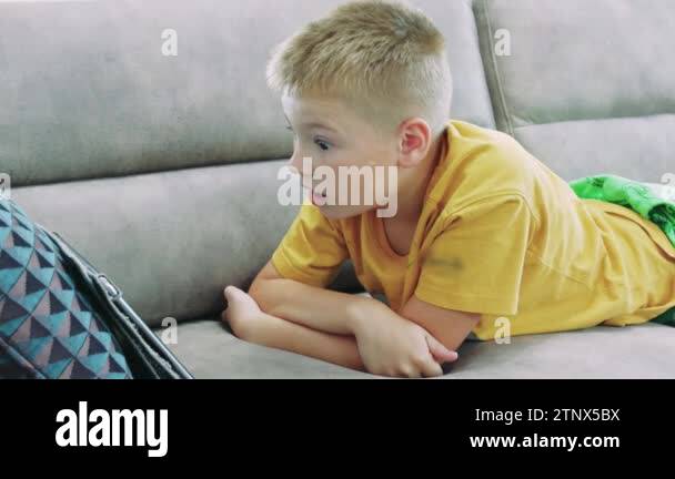 Cute 8 year old boy, looking at the tablet, he is very surprised. Emotions from what he saw ...