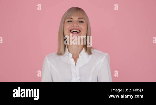 Attractive woman laughing heartily on a pink background. Her charming ...