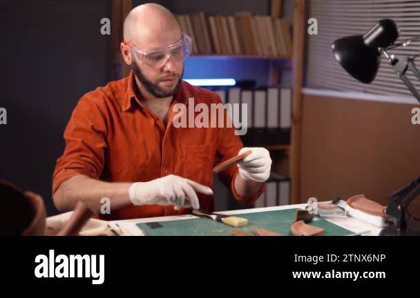 Archaeologist man working in the office late night. Studying artifacts ...