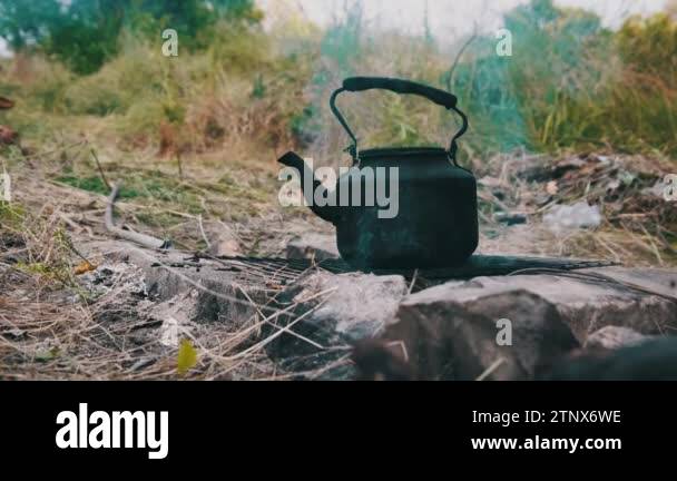 Kettle over the fire. An old vintage smoked teapot is boiling water ...