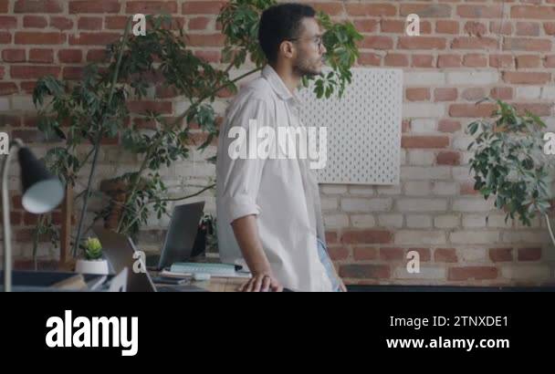 Portrait of ambitious employee African American man turning to camera and smiling in loft style ...