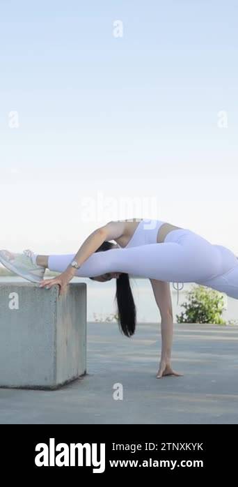 A young girl does split exercises to stretch her legs by straining her ...