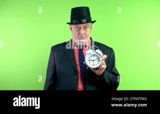 Senior man point index finger at alarm clock show control of working ...