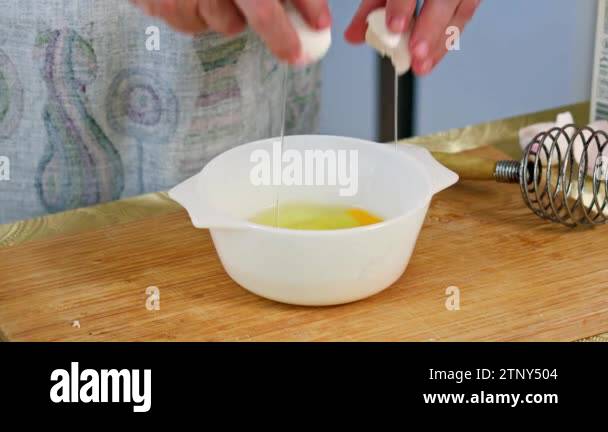 The chef breaks an egg. Break the egg into a glass bowl. The chef is ...