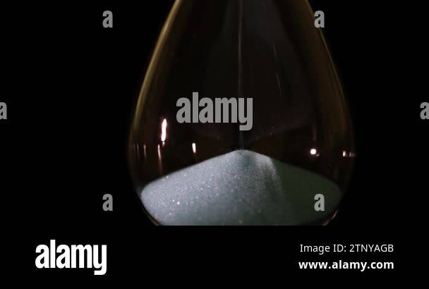 Pile of sand at bottom of hourglass and small grains of sand fall from ...