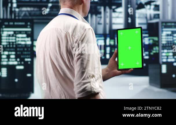 Technician in high tech data center using green screen tablet to ...