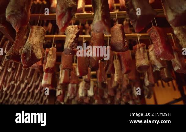 Pieces of raw beef pork with bacon are tied with rope and hung in dryer ...