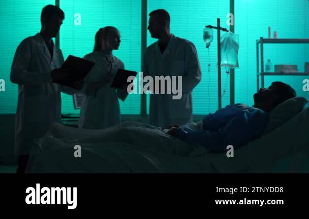 Full-sized silhouette video of three doctors standing around a patient ...