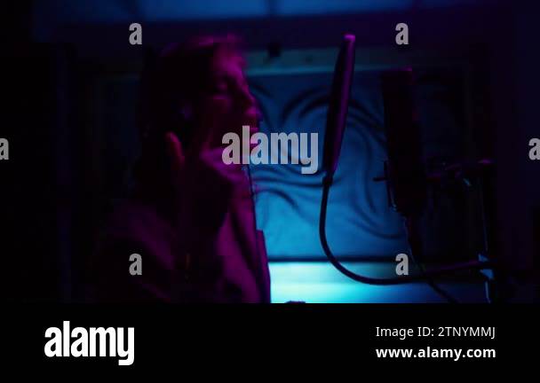 Female singer gesturing hands and singing song in neon light studio ...